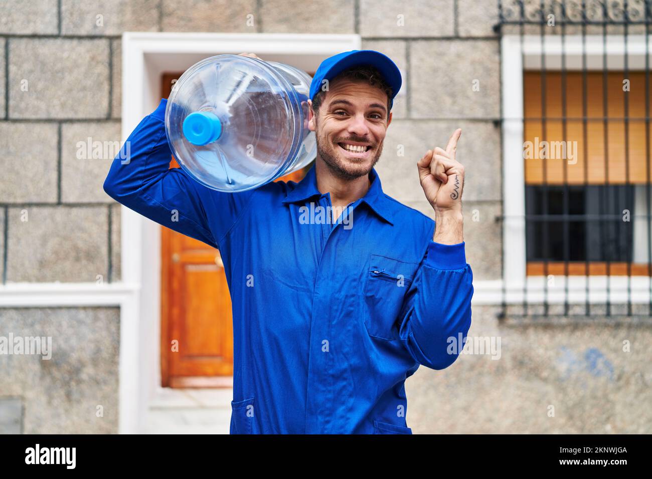 Young hispanic man holding a gallon bottle of water for delivery ...