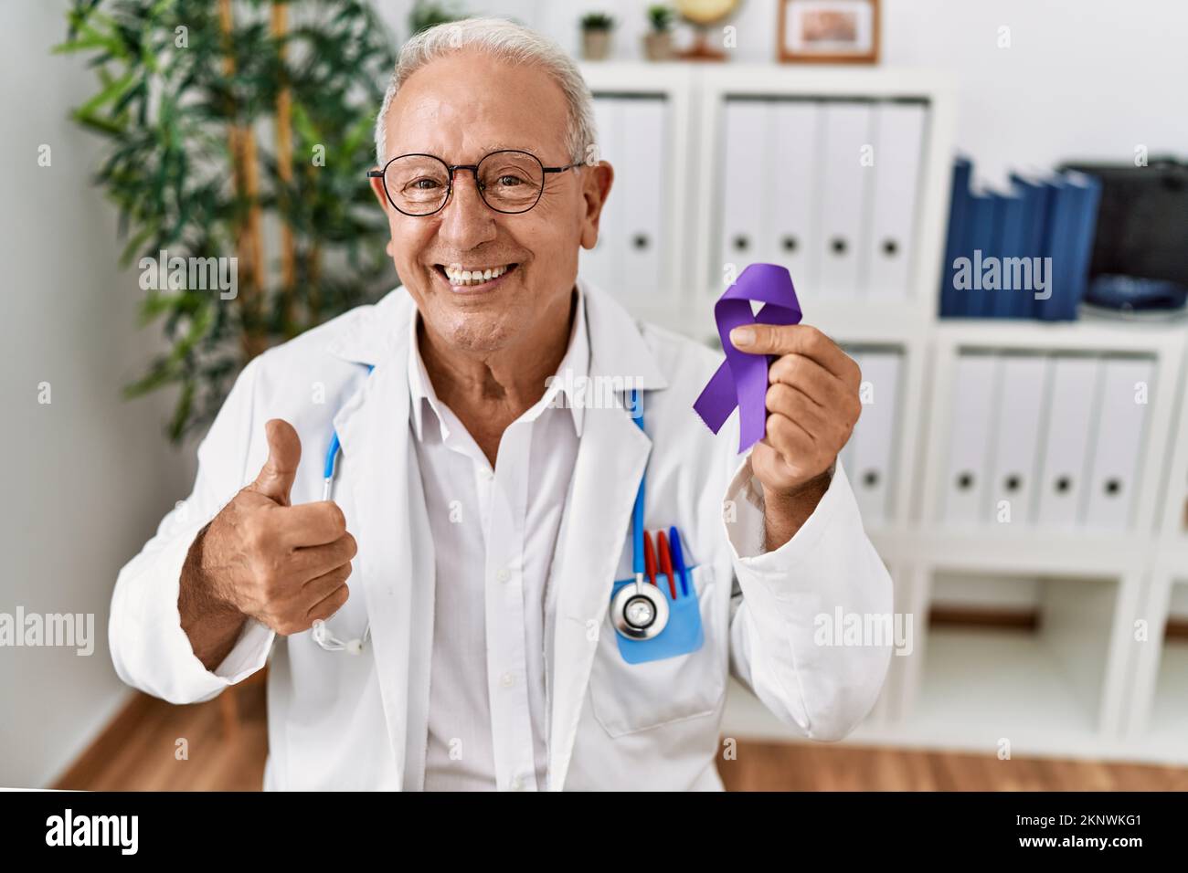 Senior doctor man holding purple ribbon awareness smiling happy and ...