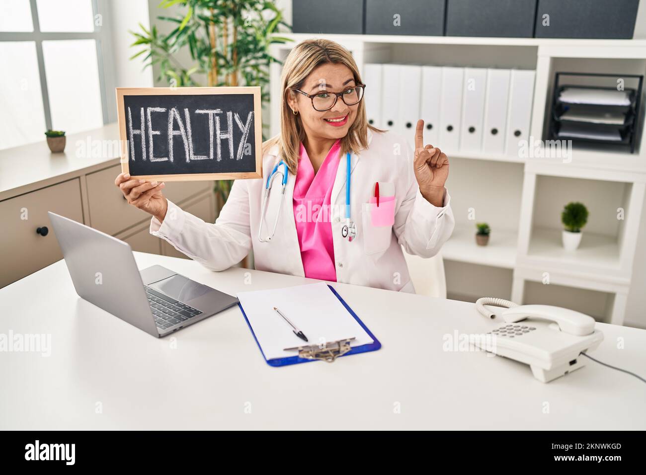 Young hispanic doctor woman holding healthy word smiling with an idea ...
