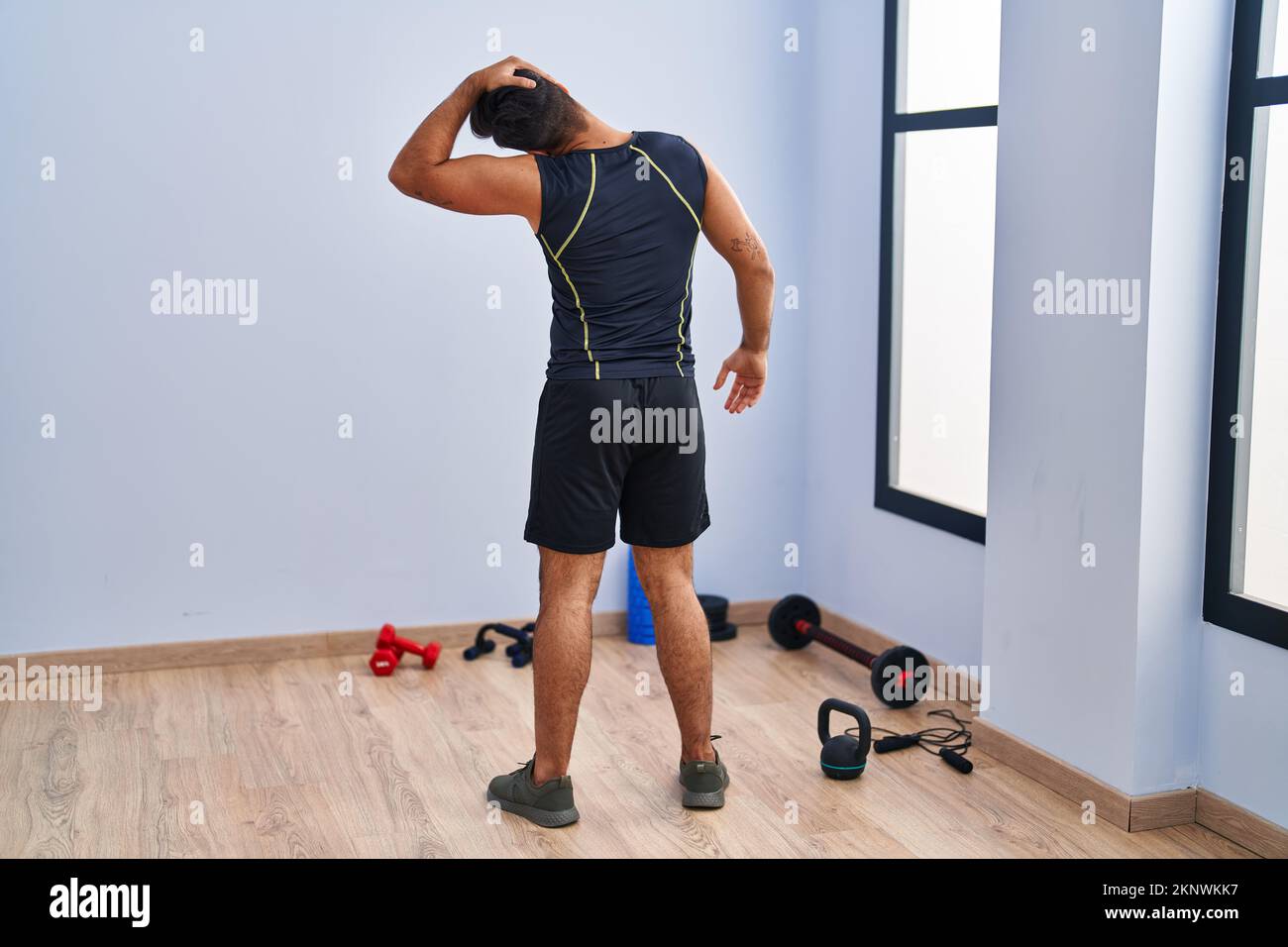 Young hispanic man stretching head standing at sport center Stock Photo ...
