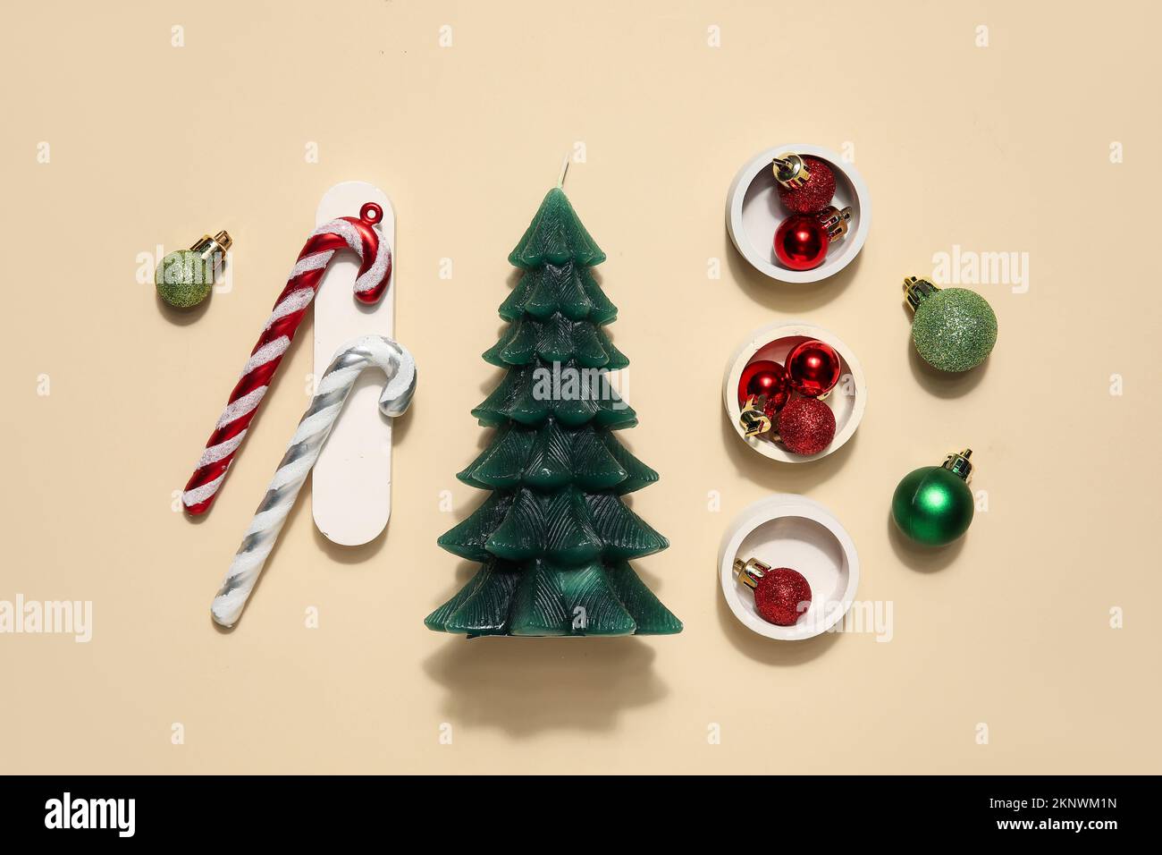 Christmas tree candle with podiums, candy canes and balls on beige ...
