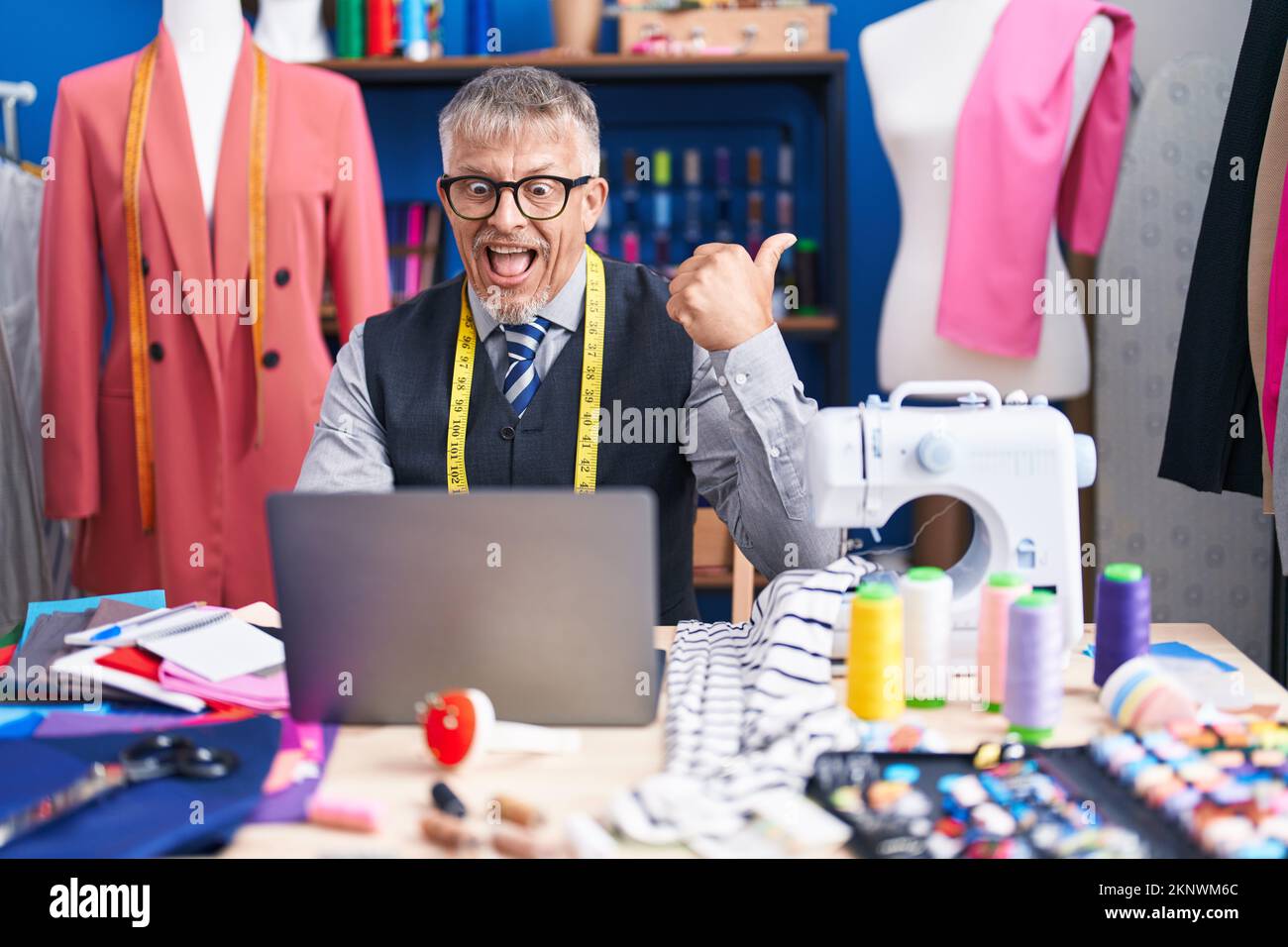 Hispanic tailor man with grey hair doing video call pointing thumb up ...
