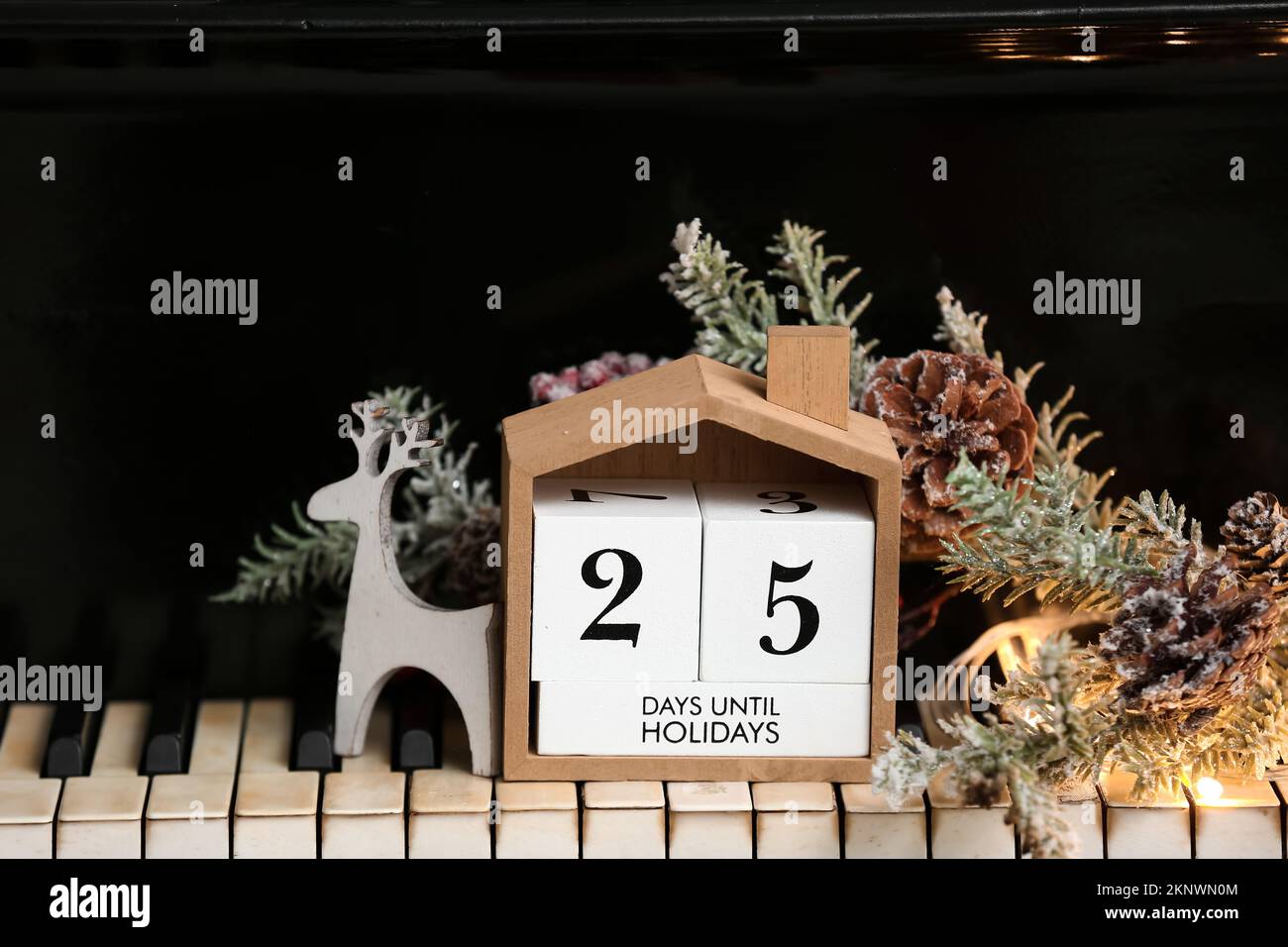 Calendar with text 25 DAYS UNTIL HOLIDAYS and Christmas decor on piano ...