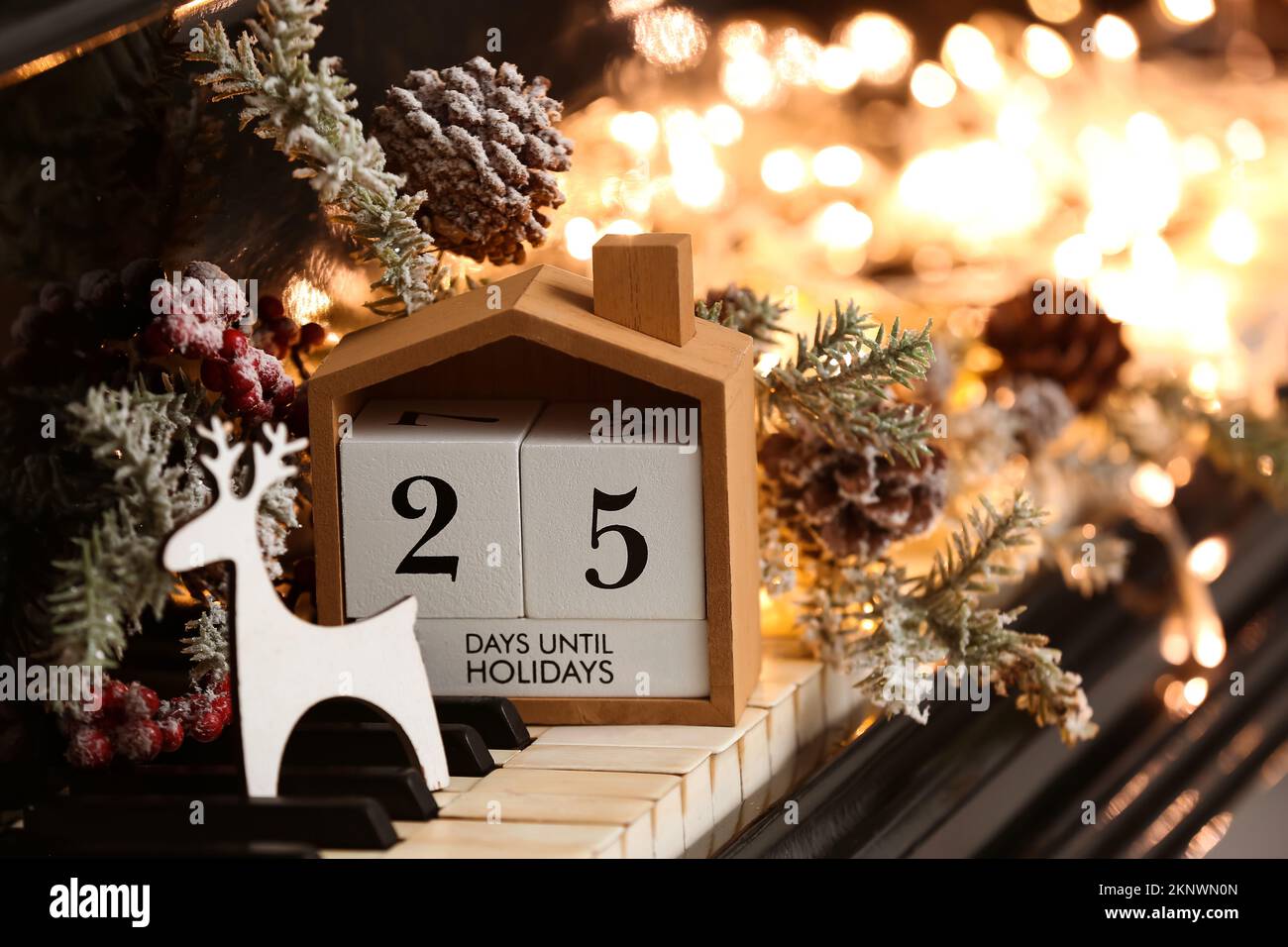 Calendar with text 25 DAYS UNTIL HOLIDAYS and Christmas decor on piano ...