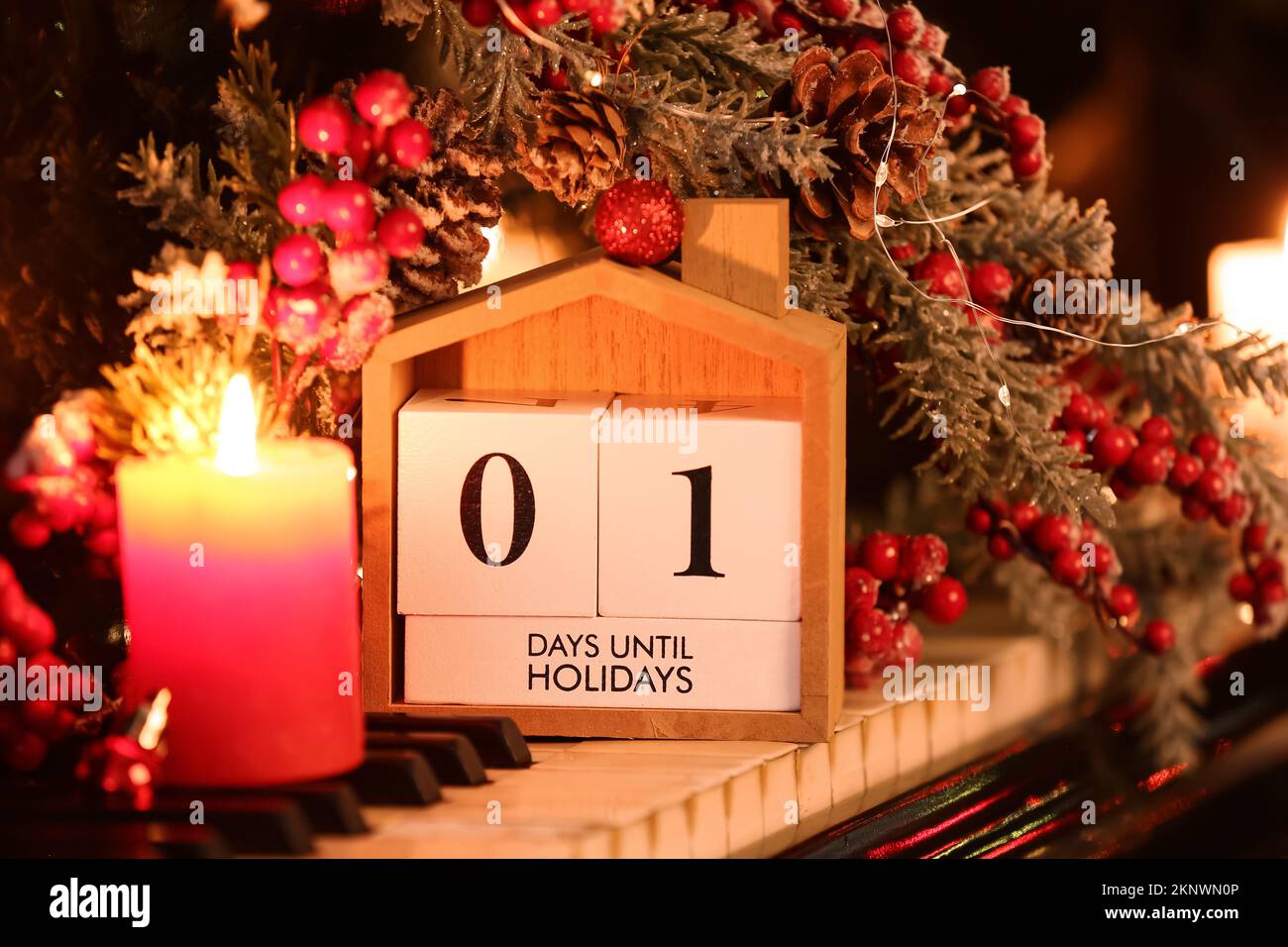 Calendar with text 1 DAY UNTIL HOLIDAYS, candle and Christmas decor on ...