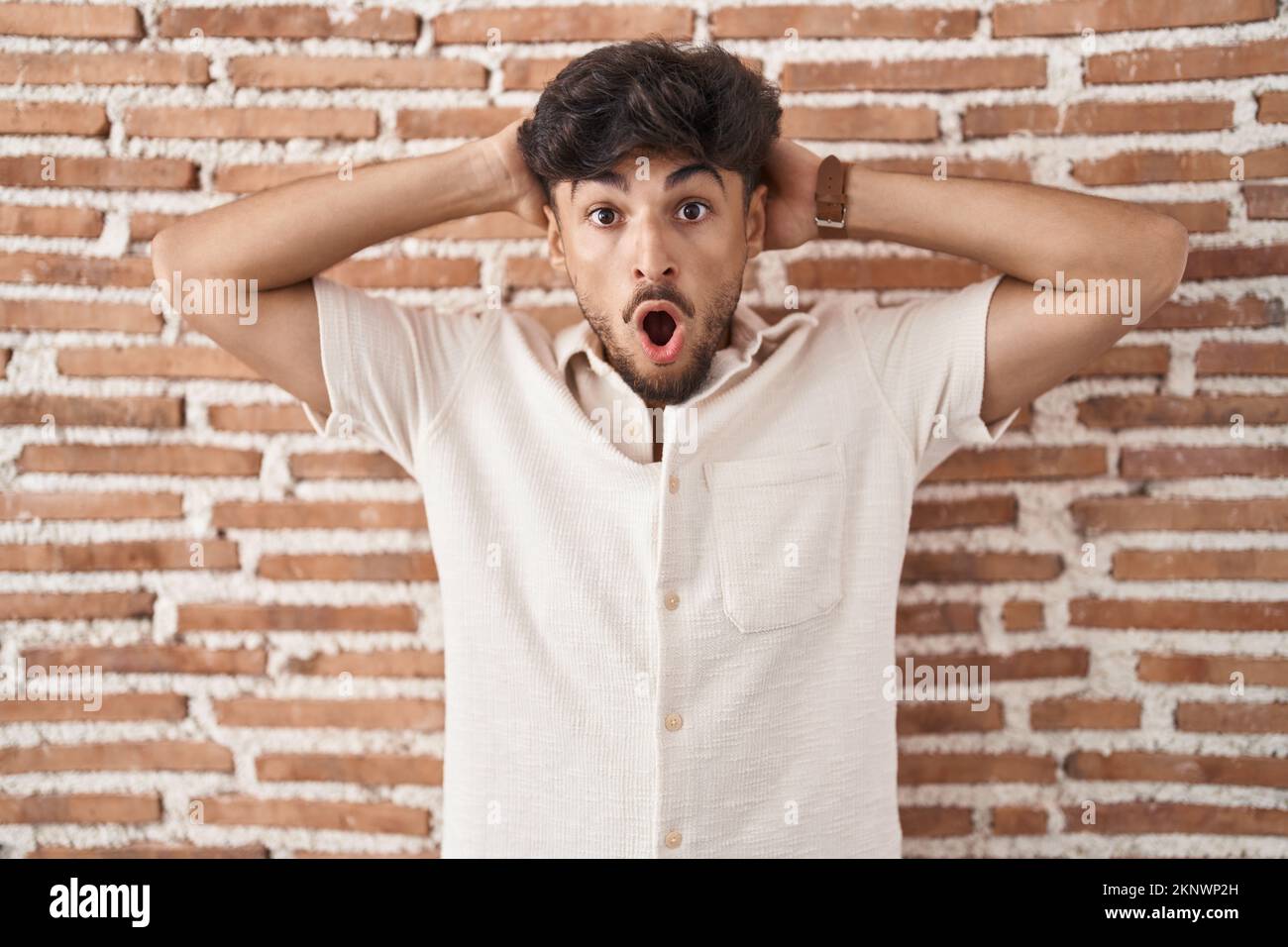 Arab man with beard standing over bricks wall background crazy and ...