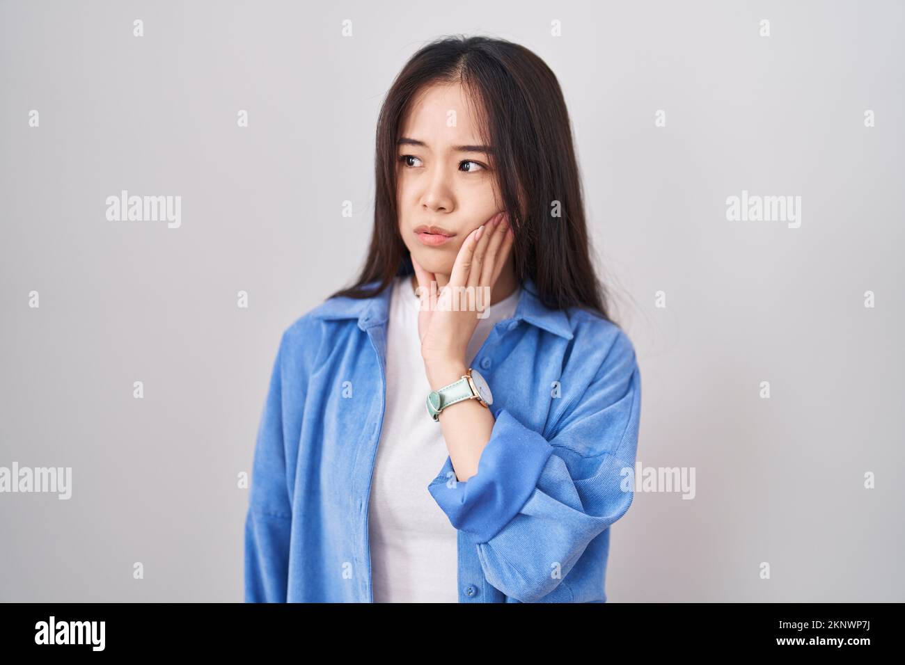 Young chinese woman standing over white background touching mouth with ...