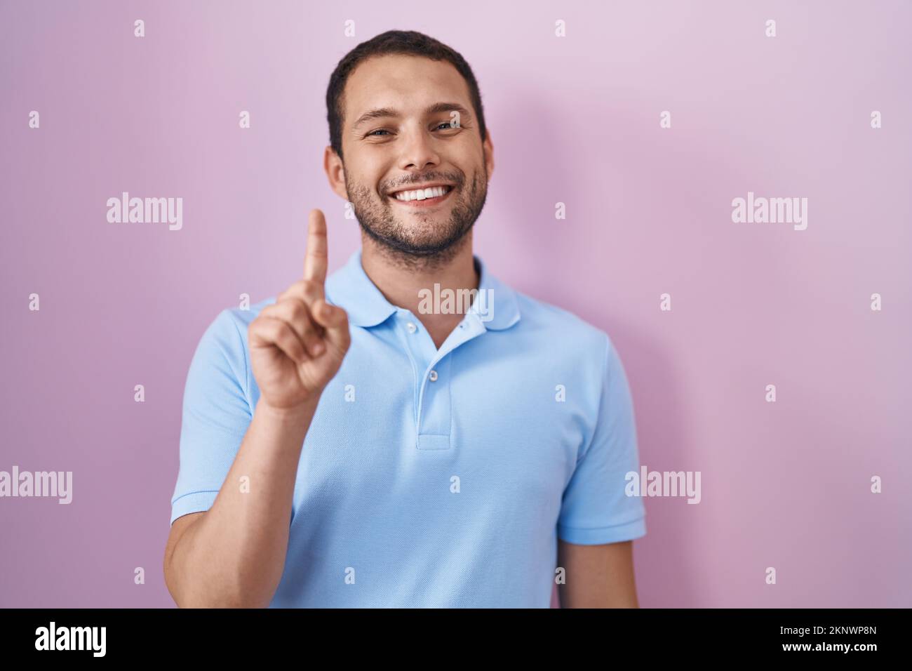 Hispanic man standing over pink background showing and pointing up with ...
