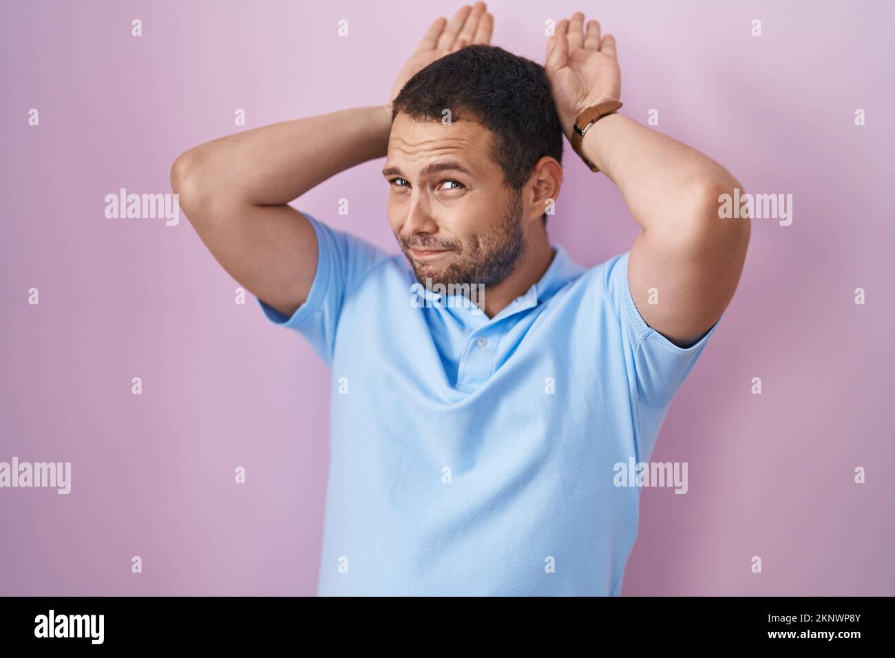Hispanic man standing over pink background doing bunny ears gesture ...