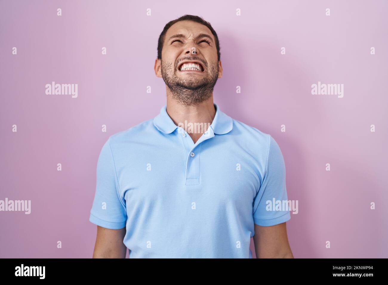 Hispanic man standing over pink background angry and mad screaming ...
