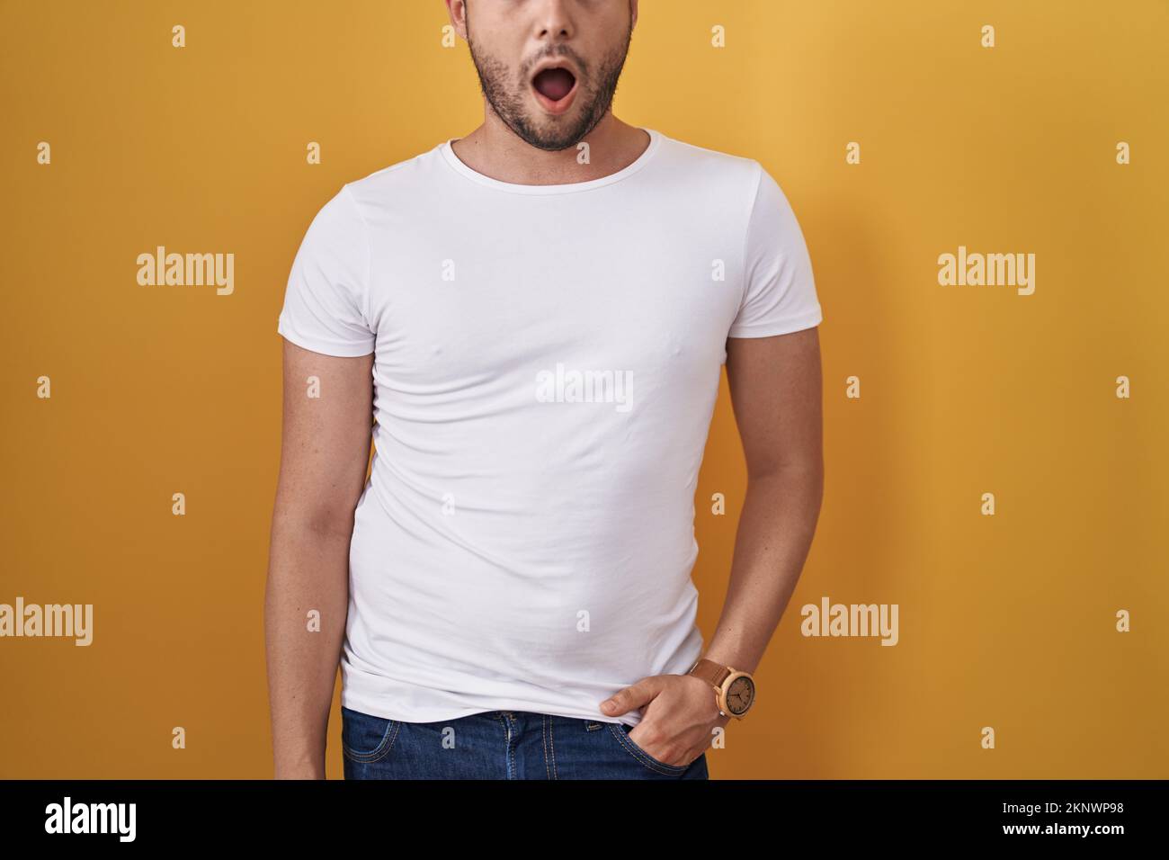 Hispanic man wearing white t shirt over yellow background scared and ...