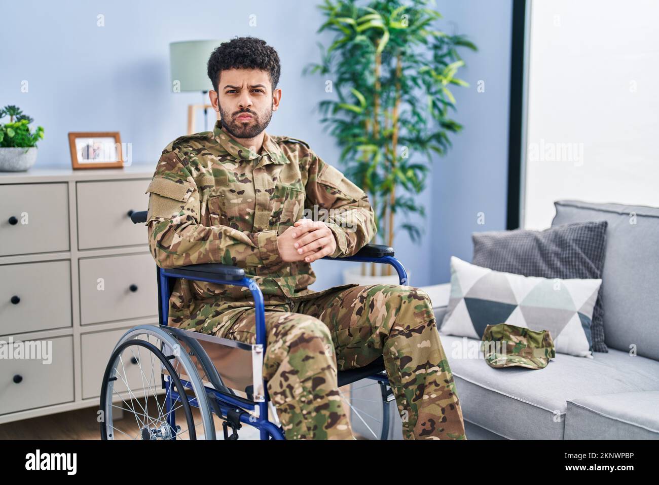Arab man wearing camouflage army uniform sitting on wheelchair puffing ...