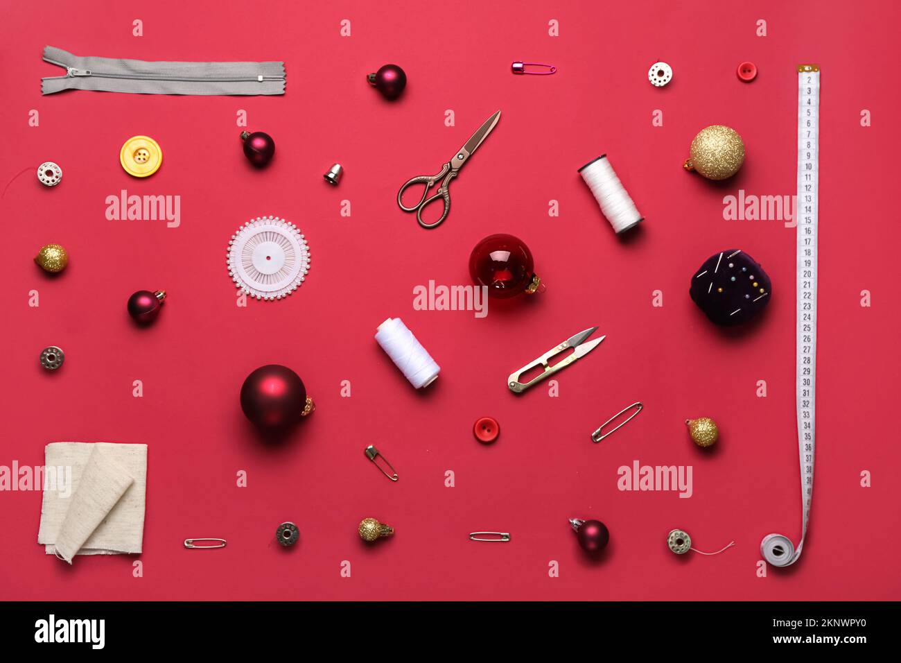 Sewing supplies with Christmas balls on red background Stock Photo - Alamy