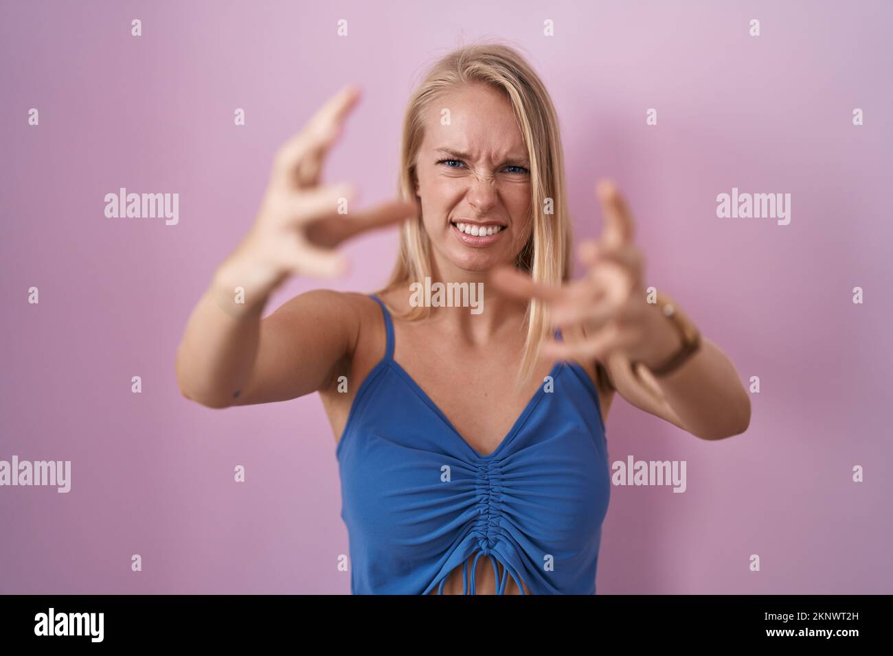Young caucasian woman standing over pink background shouting frustrated ...