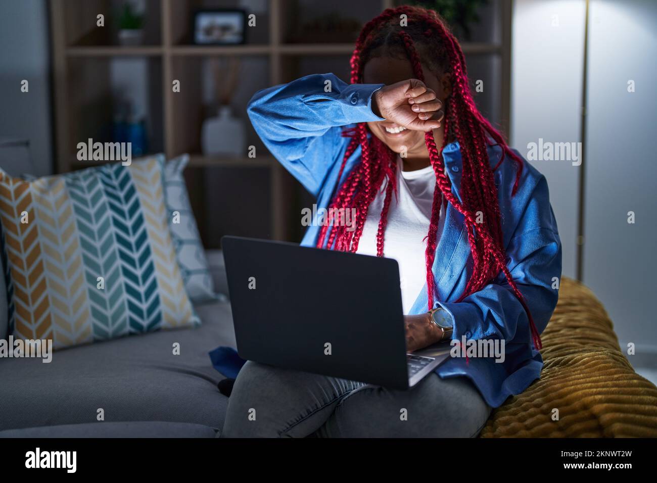 African american woman with braided hair using computer laptop at night ...