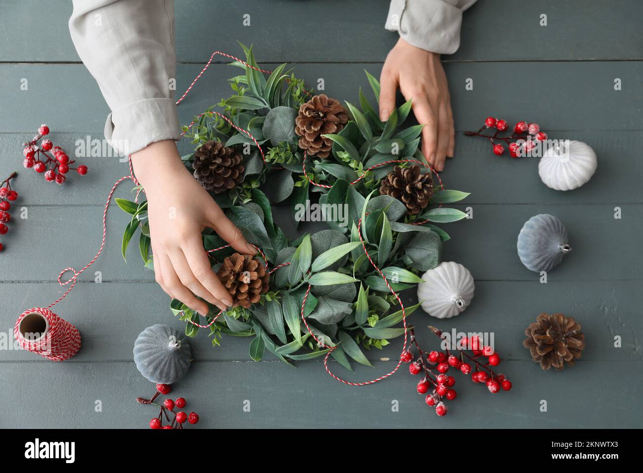 Woman making beautiful Christmas wreath on color wooden background ...