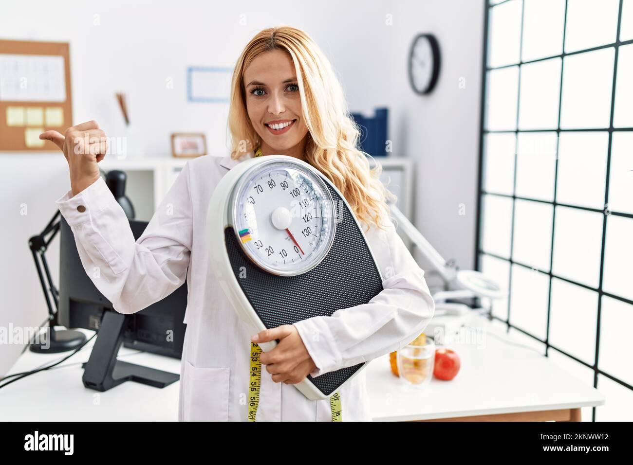 Beautiful blonde nutritionist woman holding weight machine to balance ...