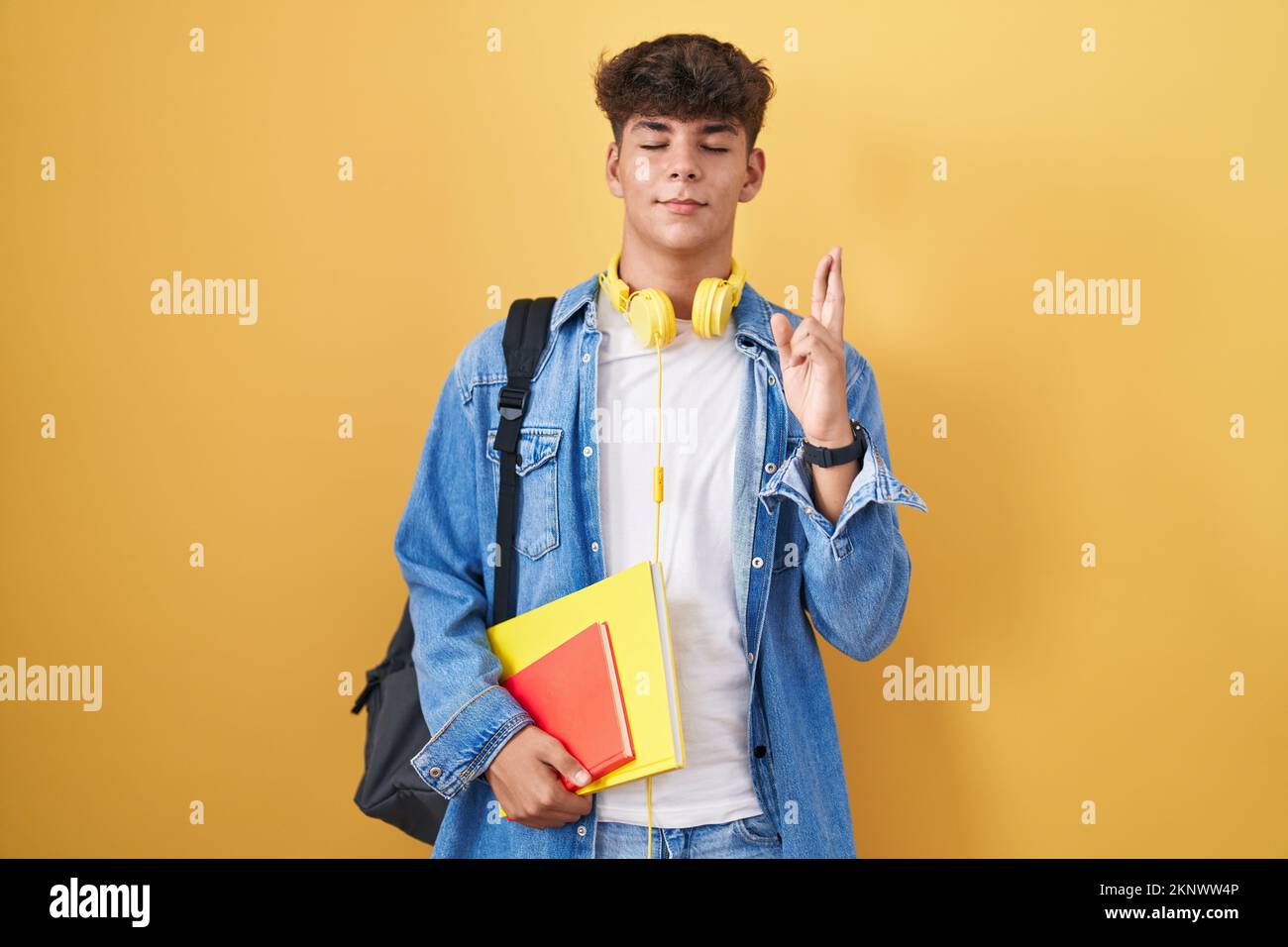 Hispanic teenager wearing student backpack and holding books gesturing ...