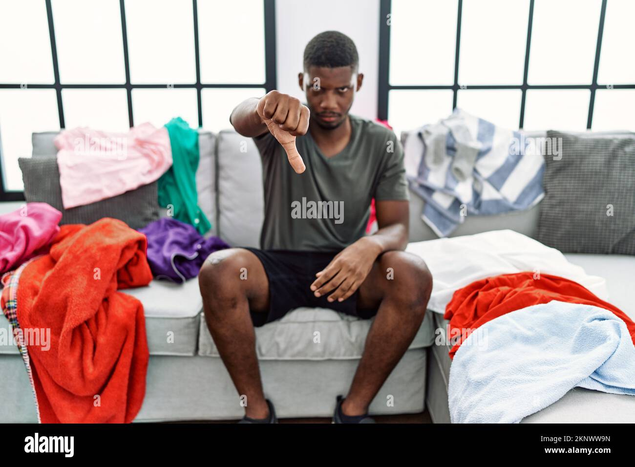 Young african american man sitting on the sofa with dirty laundry ...