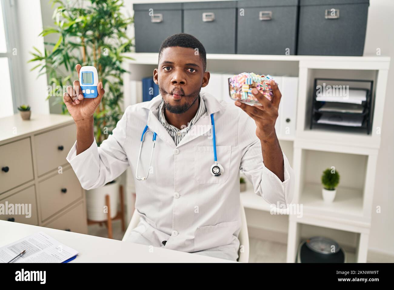 African american doctor man using glucose meter making fish face with ...