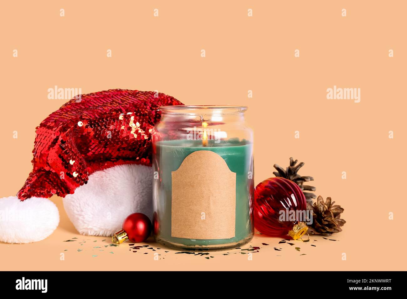 Jar with burning candle, Christmas balls, fir cones and Santa hat on ...