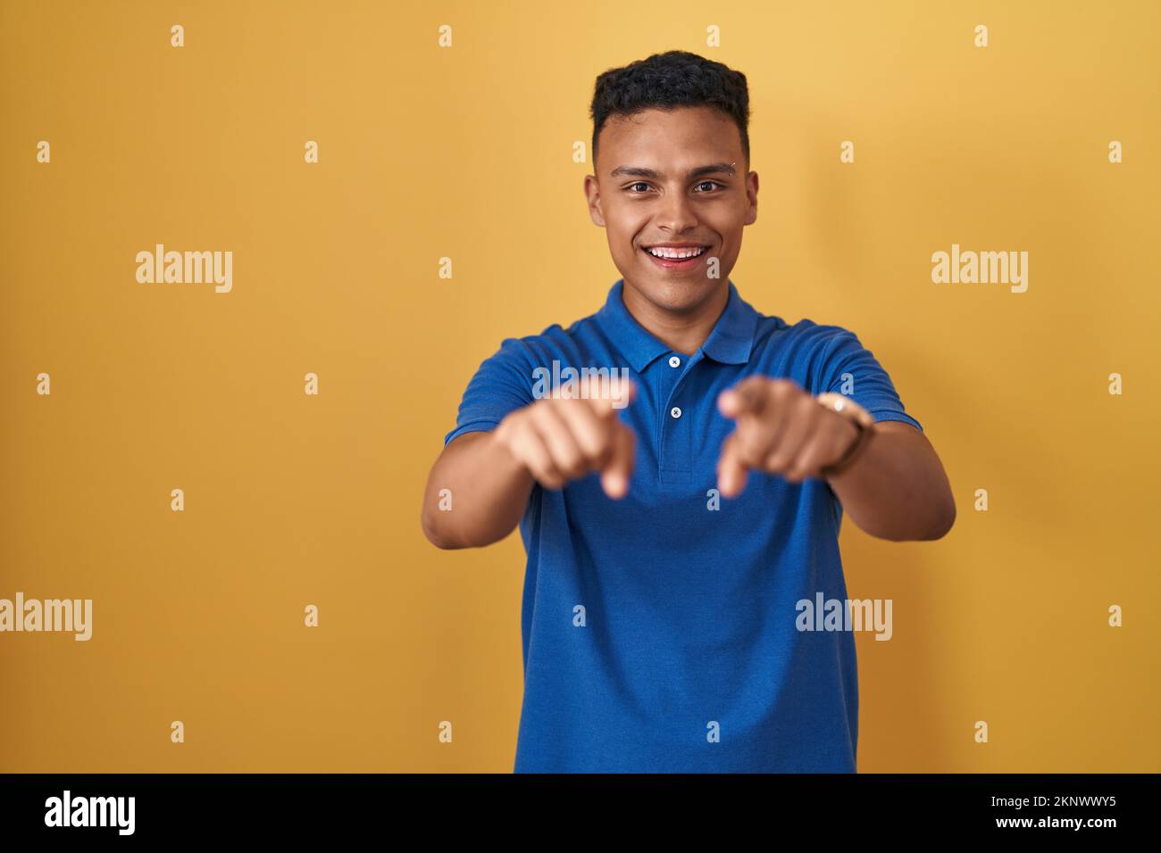 Young hispanic man standing over yellow background pointing to you and ...