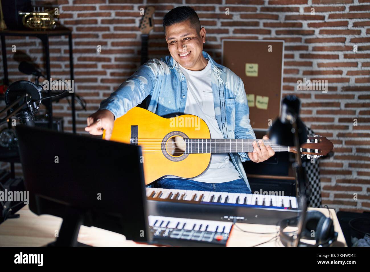 Hispanic young man playing classic guitar at music studio pointing to ...