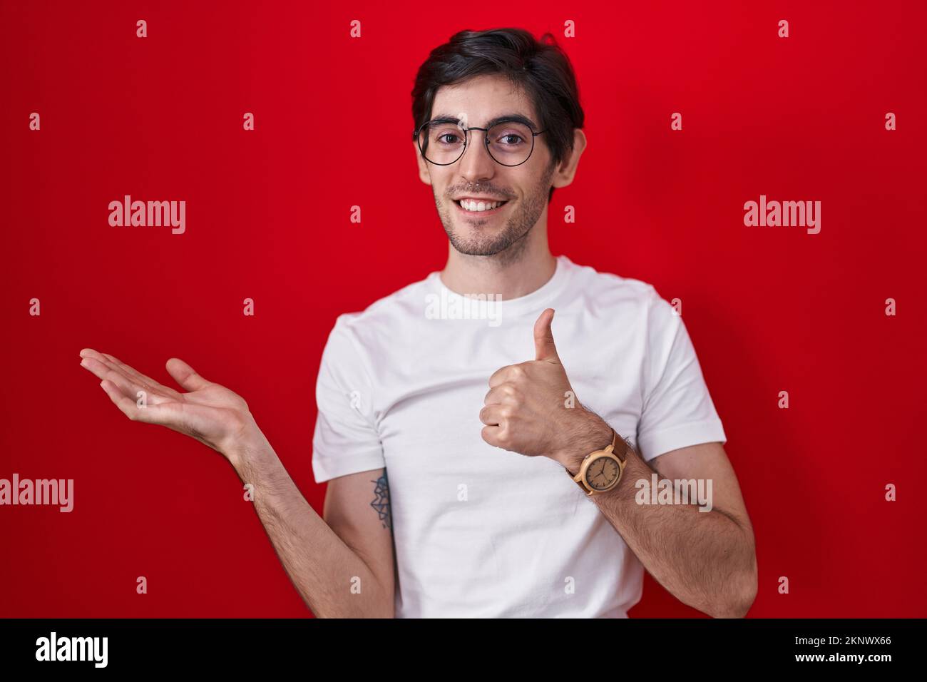 Young hispanic man standing over red background showing palm hand and ...