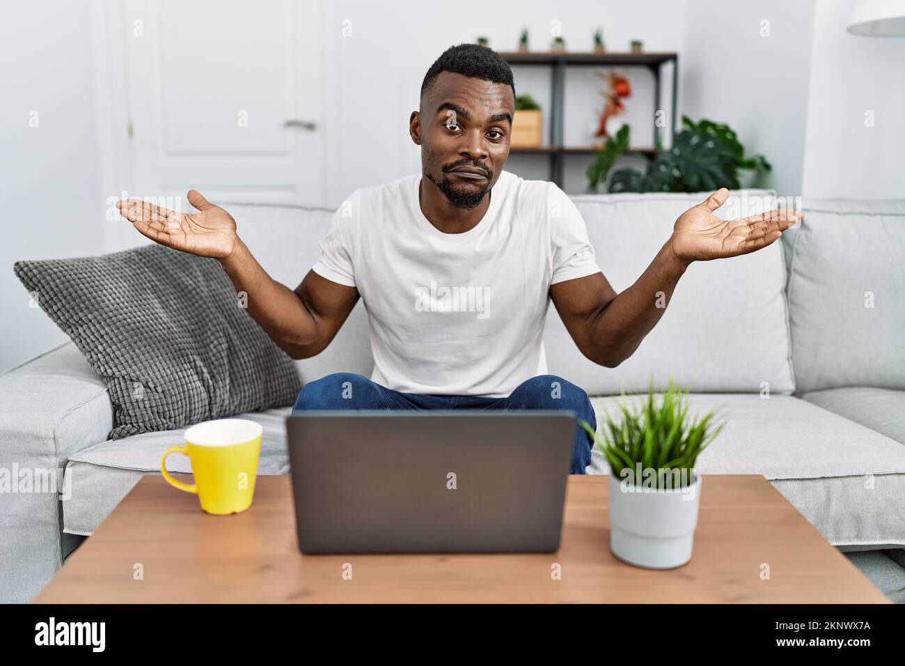 Young african man using laptop at home clueless and confused expression ...