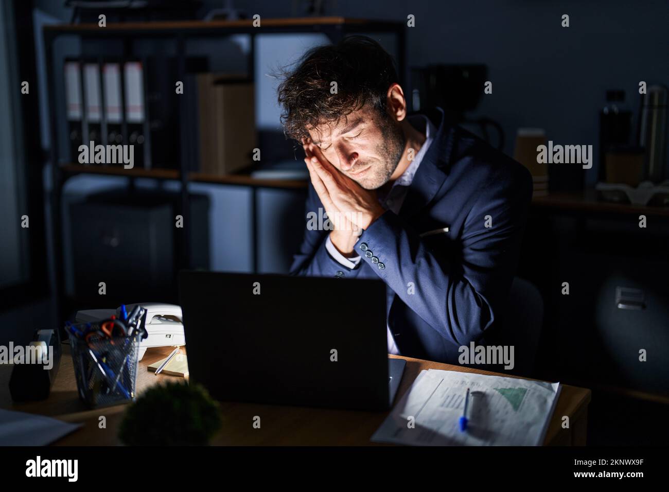 Hispanic young man working at the office at night sleeping tired ...