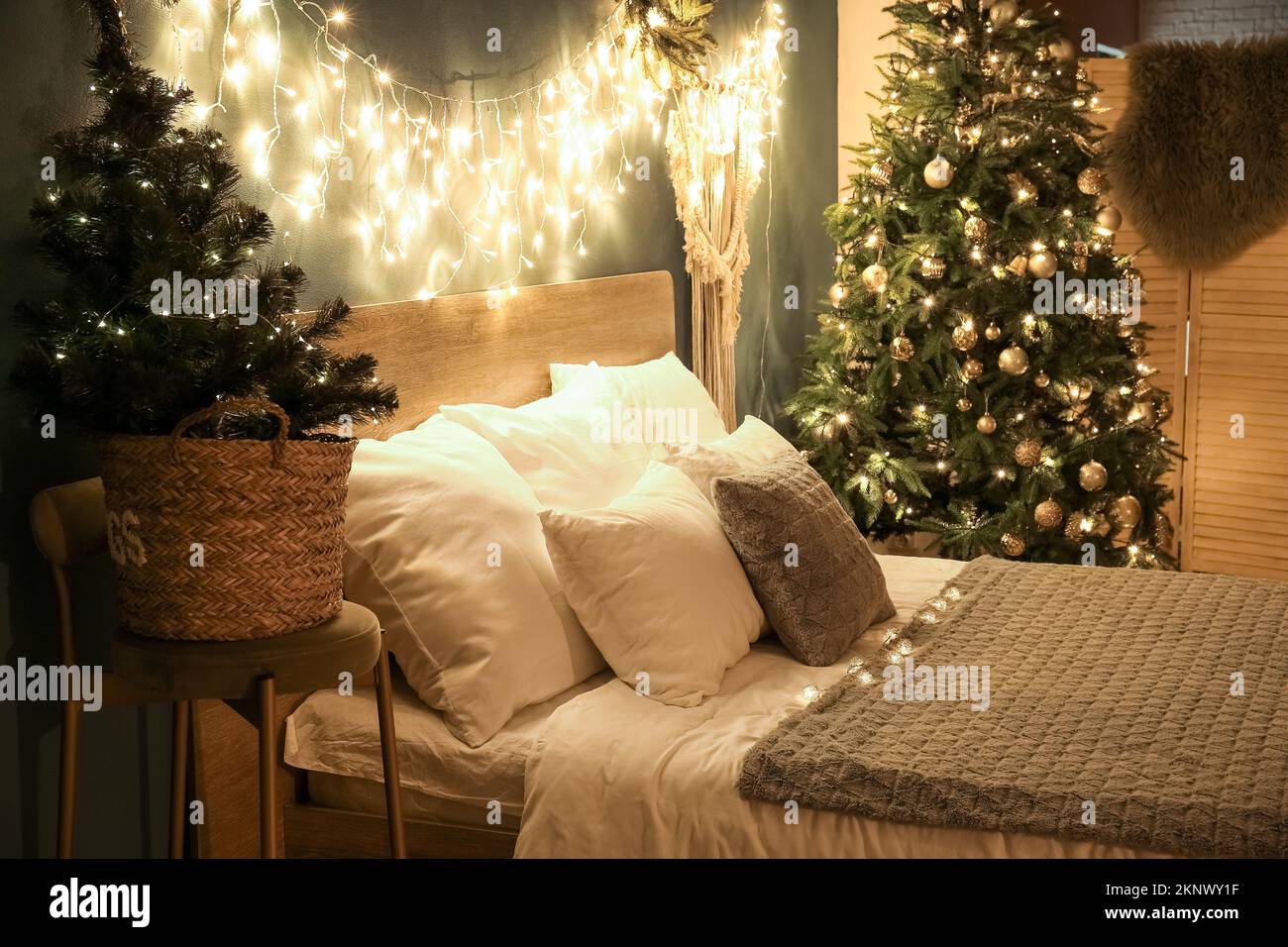Interior of bedroom with Christmas trees and glowing lights at night ...