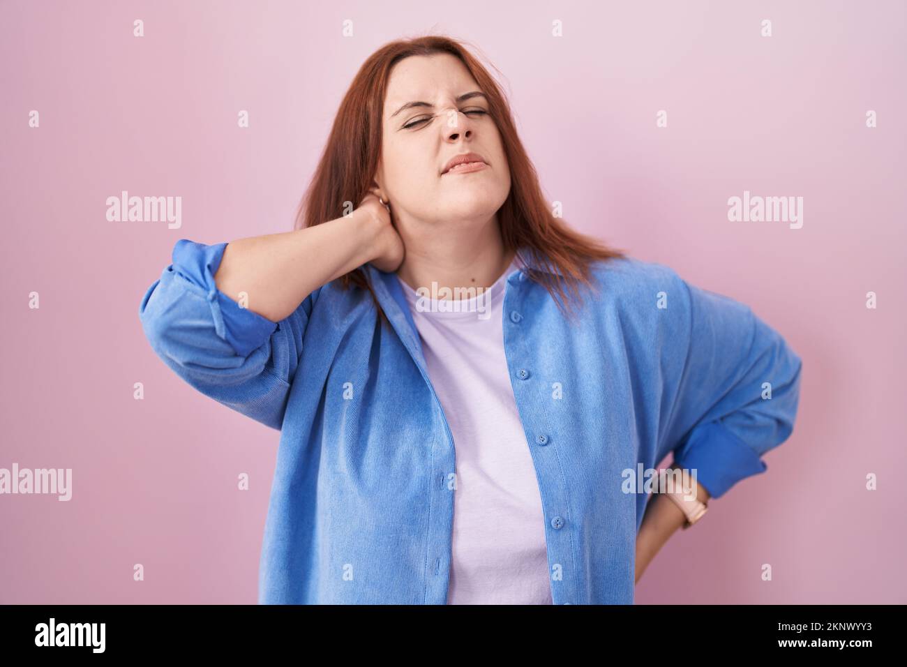 Young hispanic woman with red hair standing over pink background ...