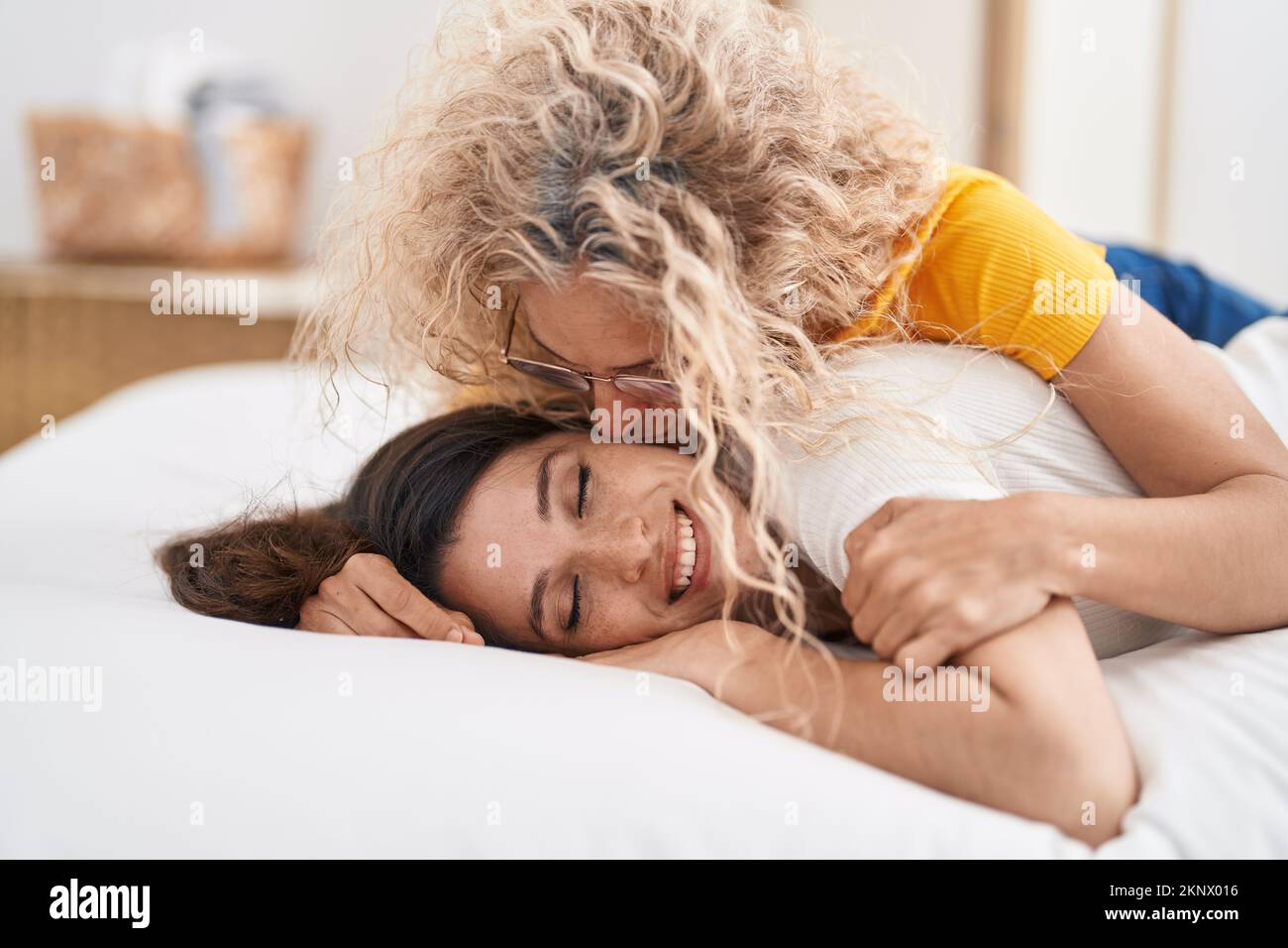 Two Women Mother And Daughter Hugging Each Other Lying On Bed At
