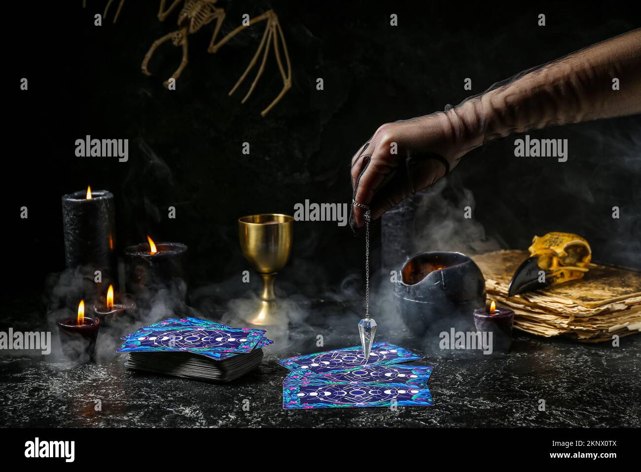 Fortune teller using pendulum and tarot cards to read future on dark ...