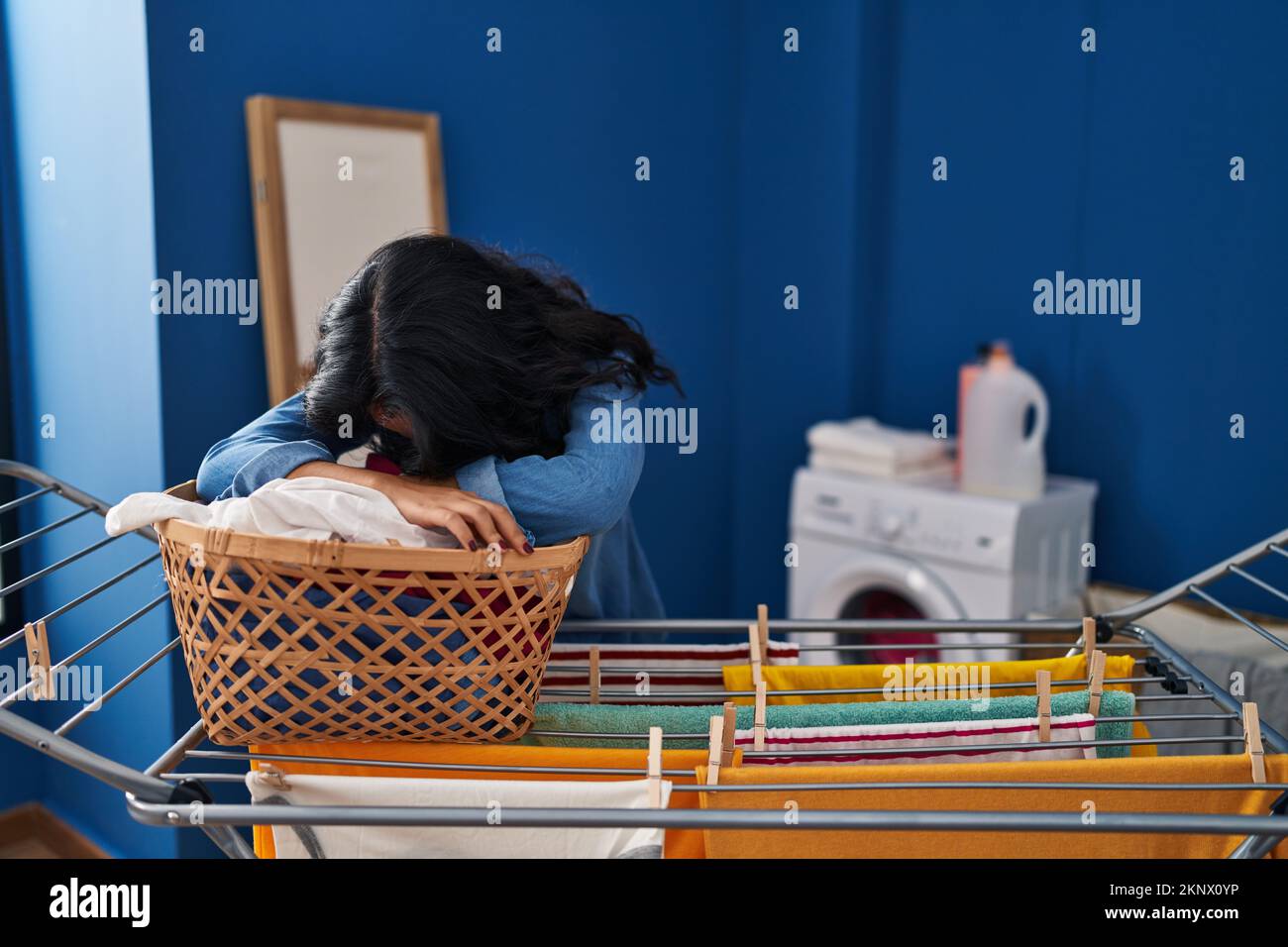 Young asian woman hanging clothes at clothesline with sad expression ...