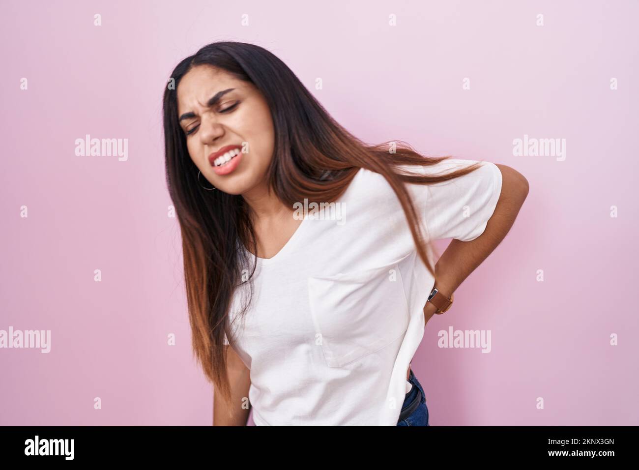 Young arab woman standing over pink background suffering of backache ...