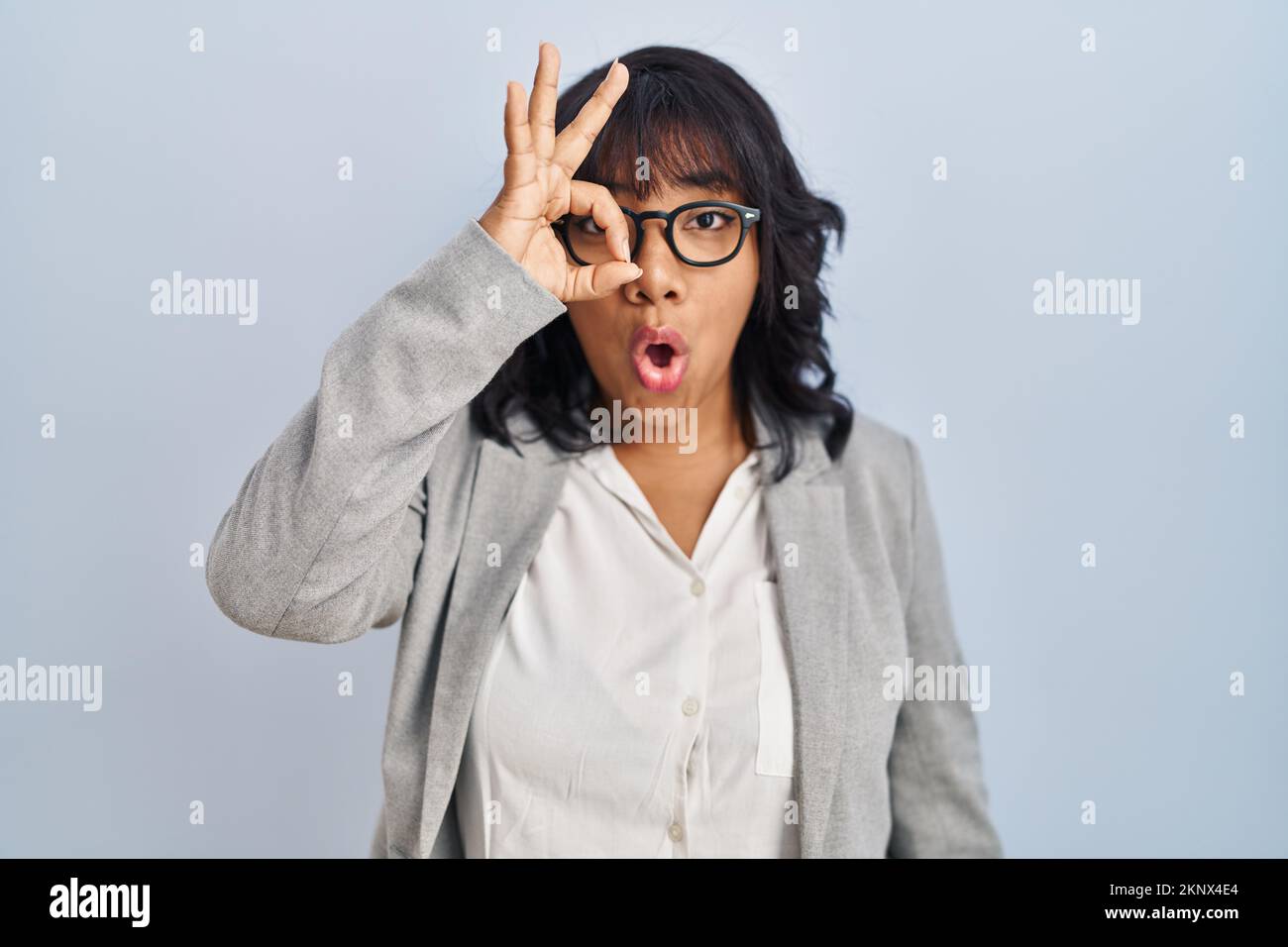 Hispanic woman standing over isolated background doing ok gesture ...