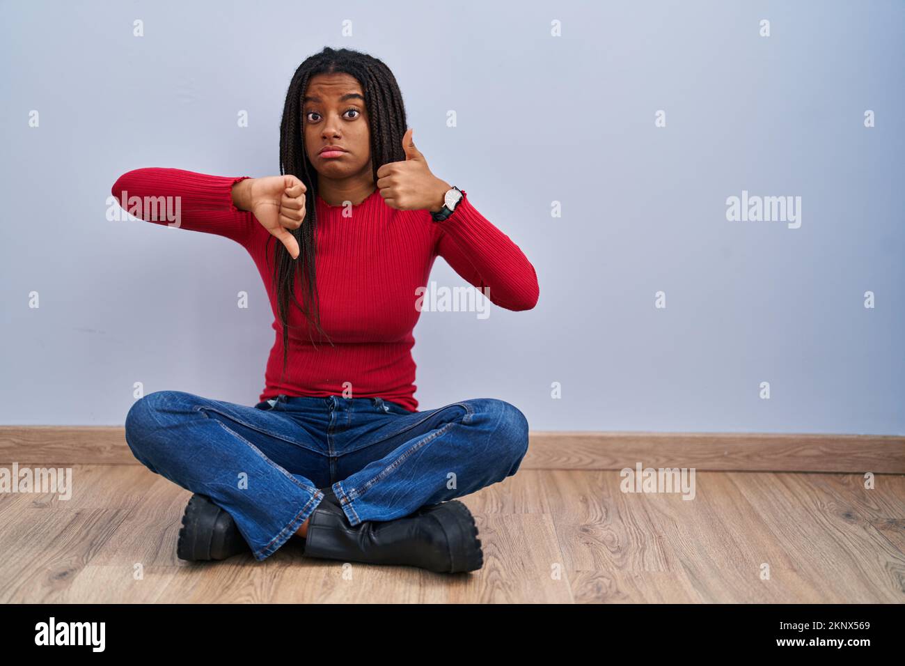 Young african american with braids sitting on the floor at home doing ...