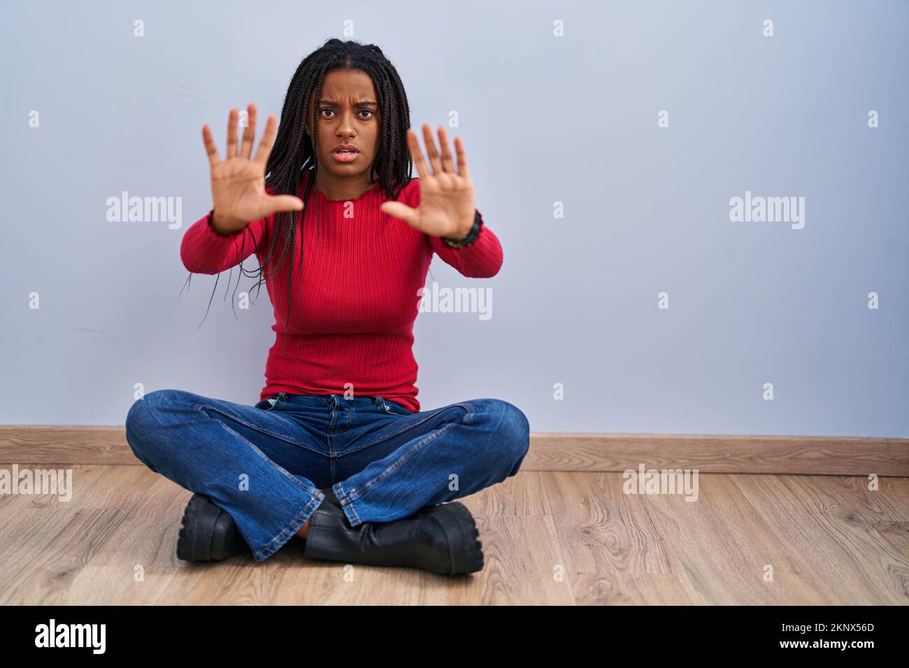 Young african american with braids sitting on the floor at home doing ...