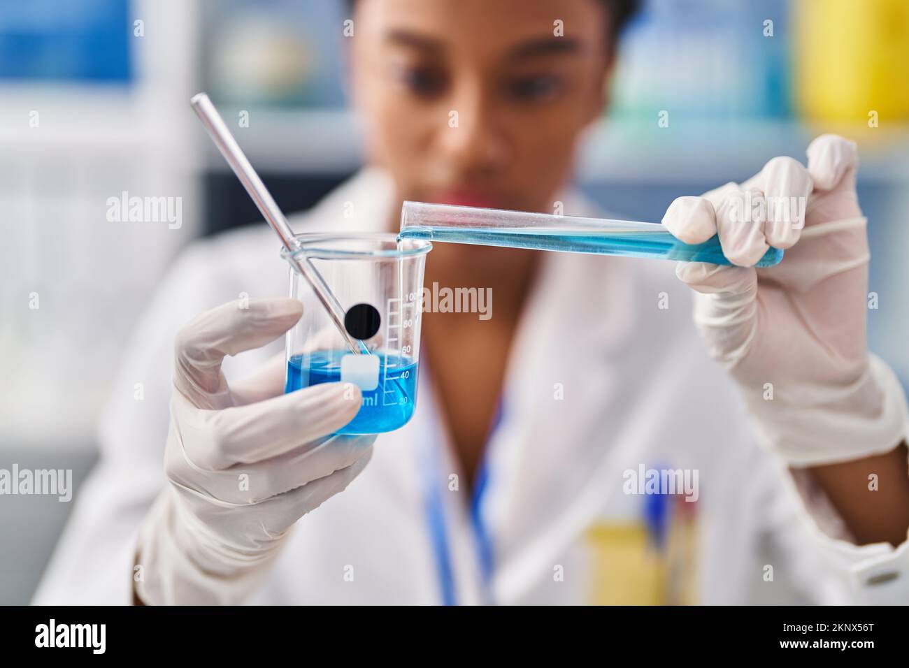African american woman scientist pouring liquid on glass at laboratory ...