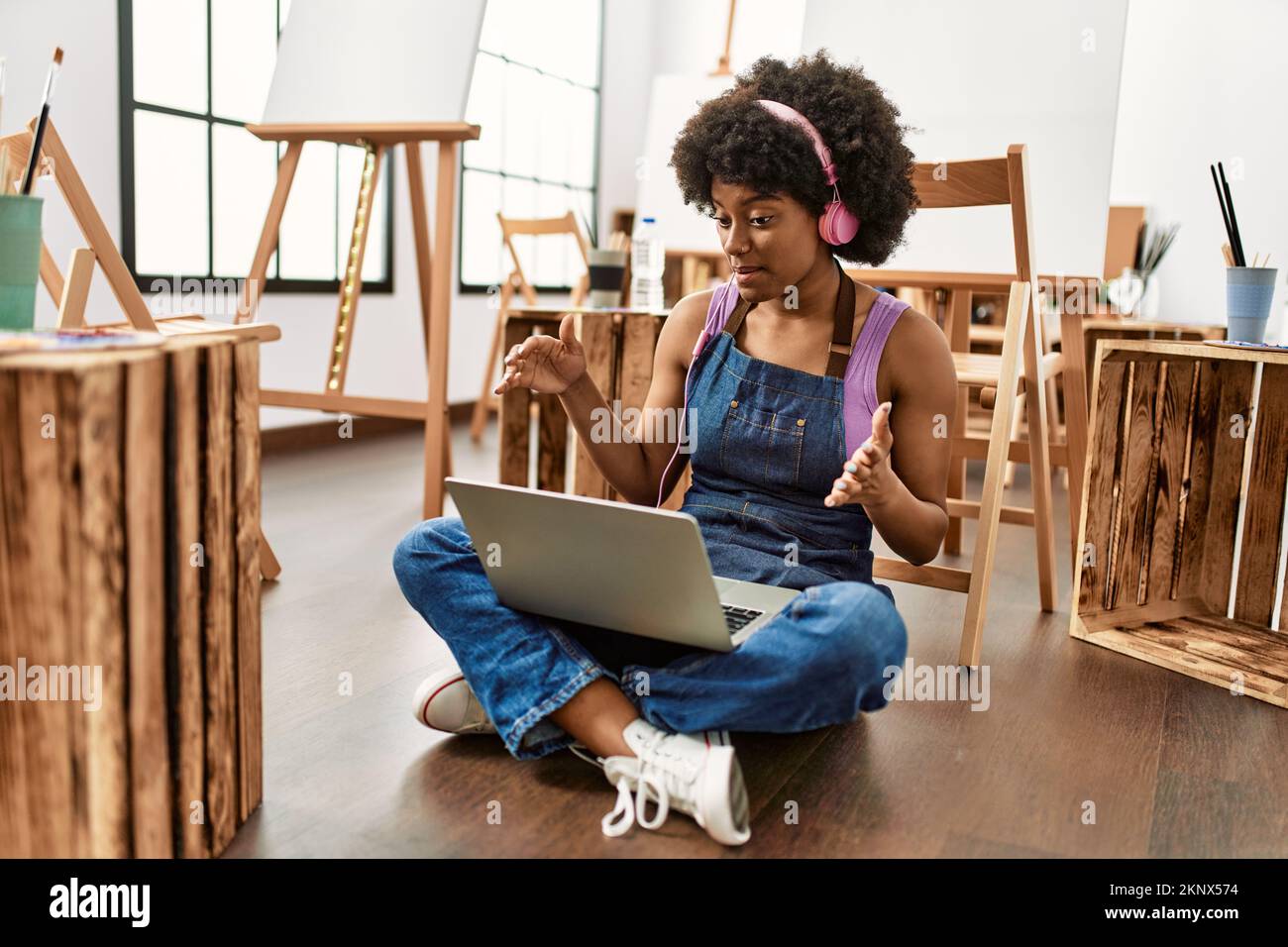 Young african american woman using laptop and headphones at art studio ...