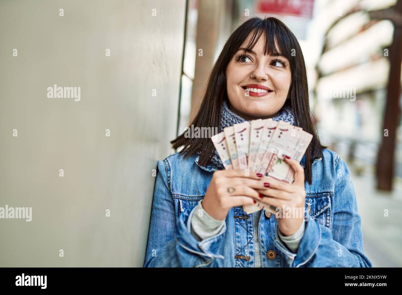 Young brunette woman holding arabia saudi riyal banknotes leaning on ...