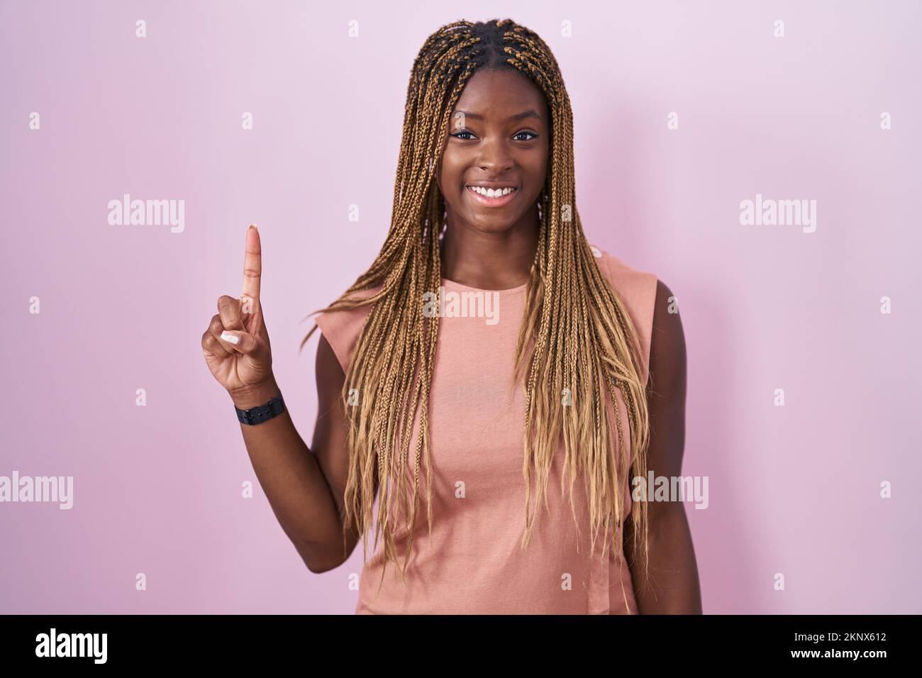 African american woman with braided hair standing over pink background ...