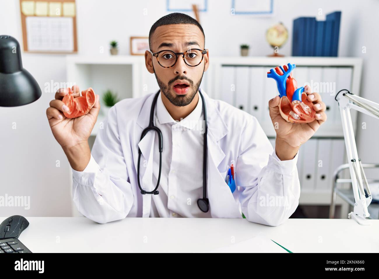 African american doctor man holding anatomical heart at the clinic ...