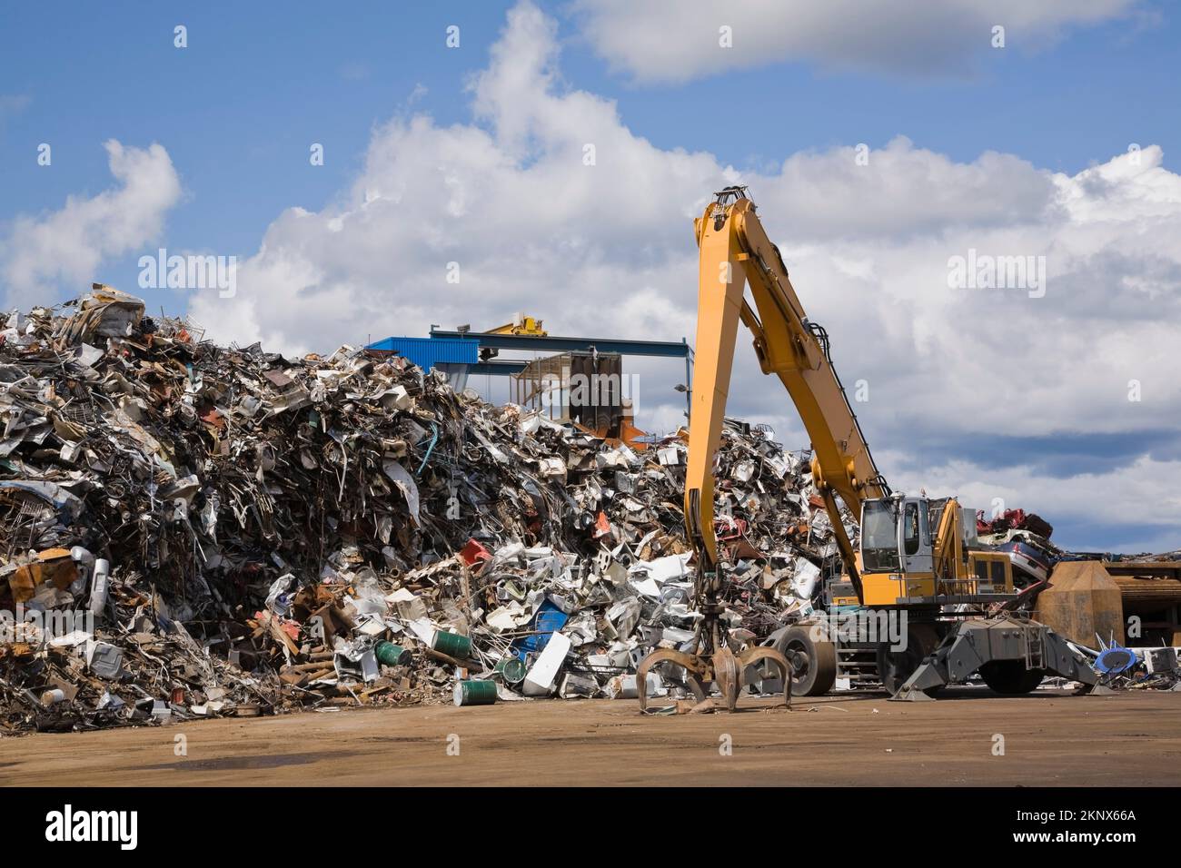 Crane loader fitted with grappling arm in front of pile of discarded ...