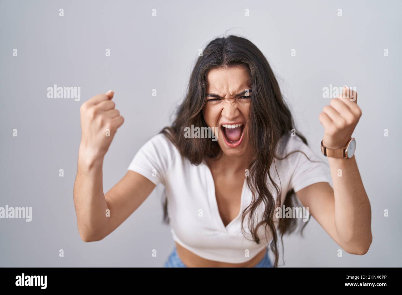 Young teenager girl standing over white background angry and mad ...