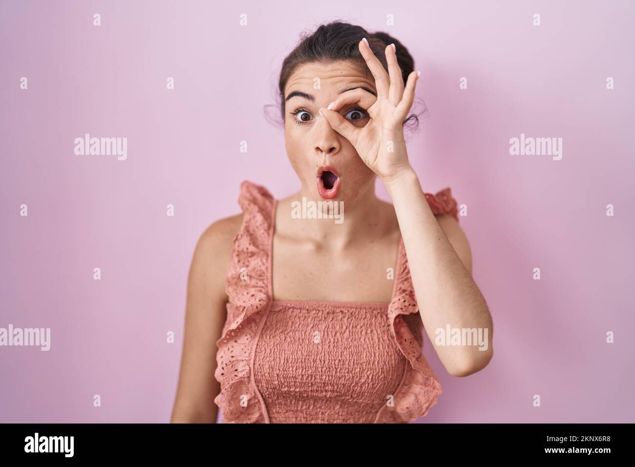 Young teenager girl standing over pink background doing ok gesture ...
