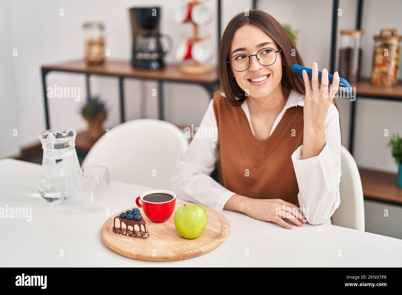 Young beautiful hispanic woman having breakfast listening voice message ...