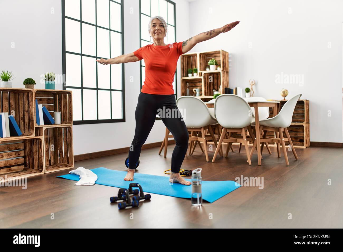 Middle age grey-haired woman smiling confident training yoga at home ...