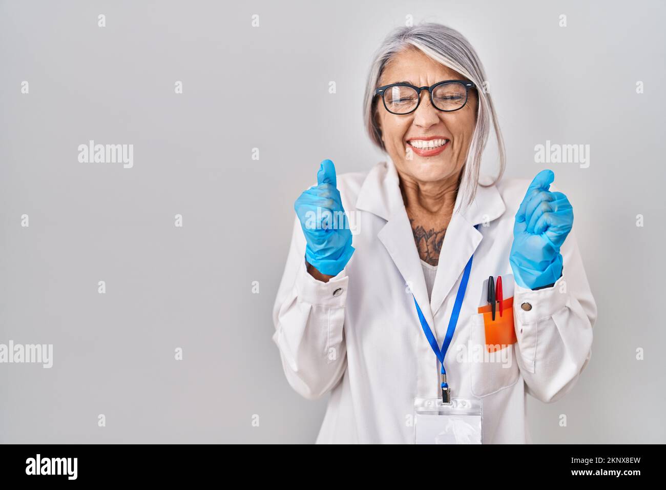 Middle age woman with grey hair wearing scientist robe excited for ...